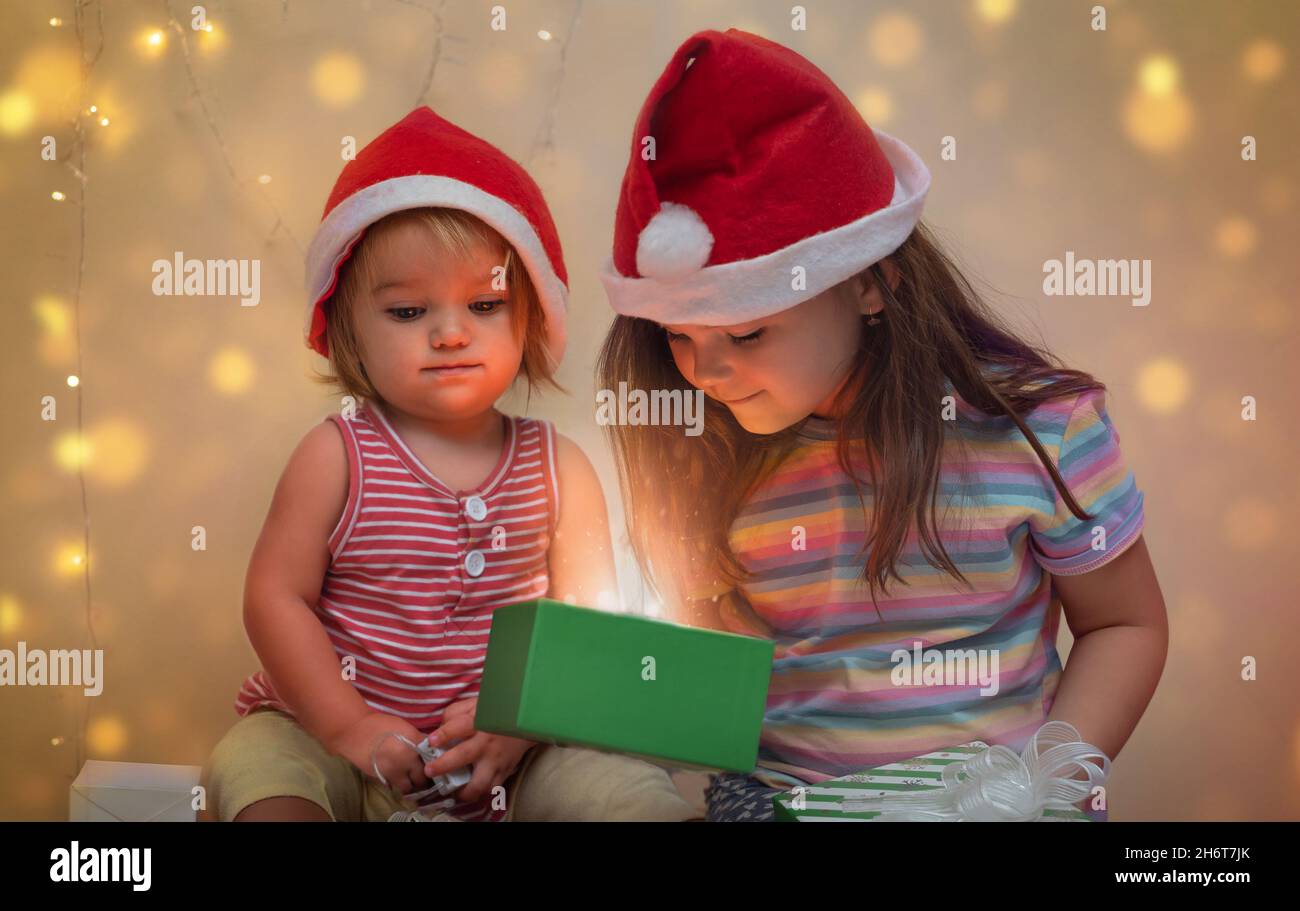 Two children sisters peek into the gift box together Stock Photo - Alamy