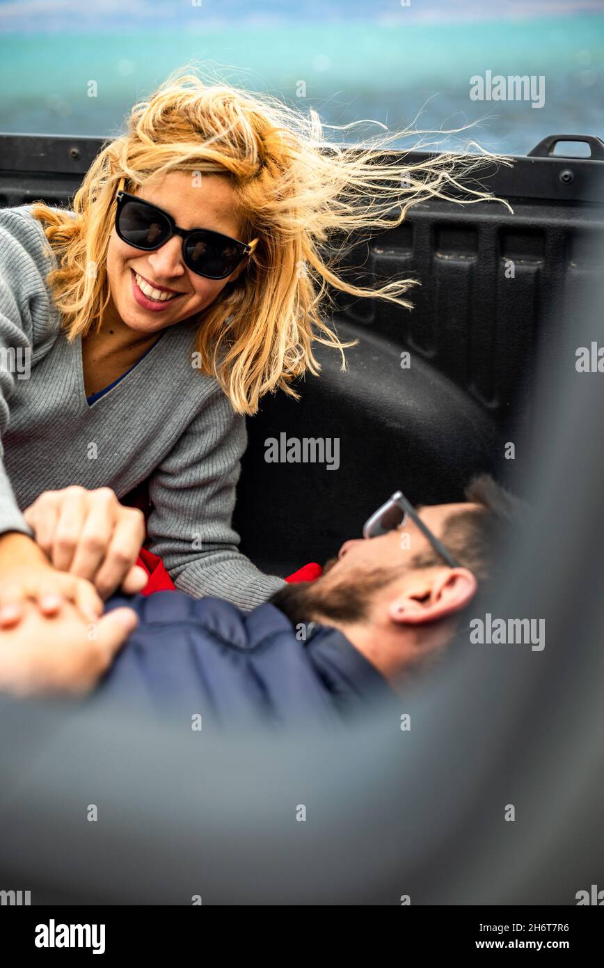 Lovely cheerful Argentinian couple cuddling in a cargo bed of a truck ...