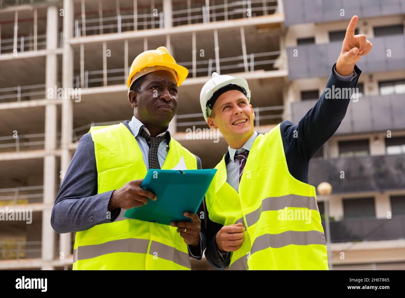 Young civil engineer discussing a construction plan with a colleague ...