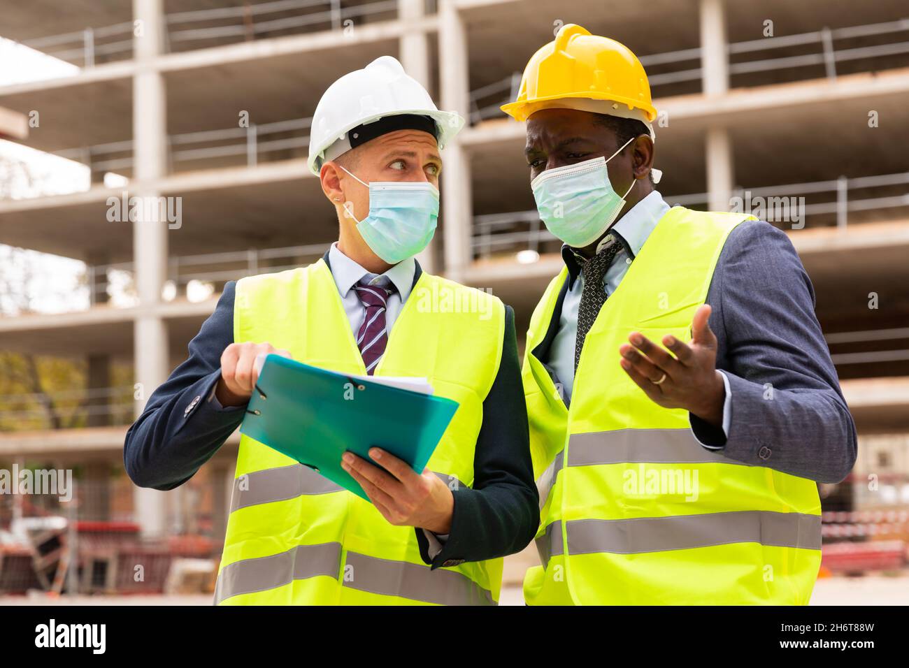 Engineers in masks standing on construction site Stock Photo - Alamy