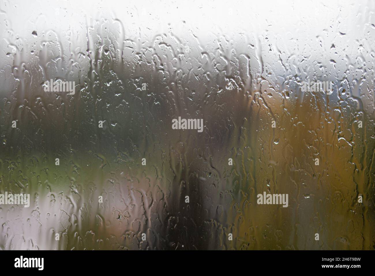 Rainy day through the window on cloudy grey sky and city buildings ...