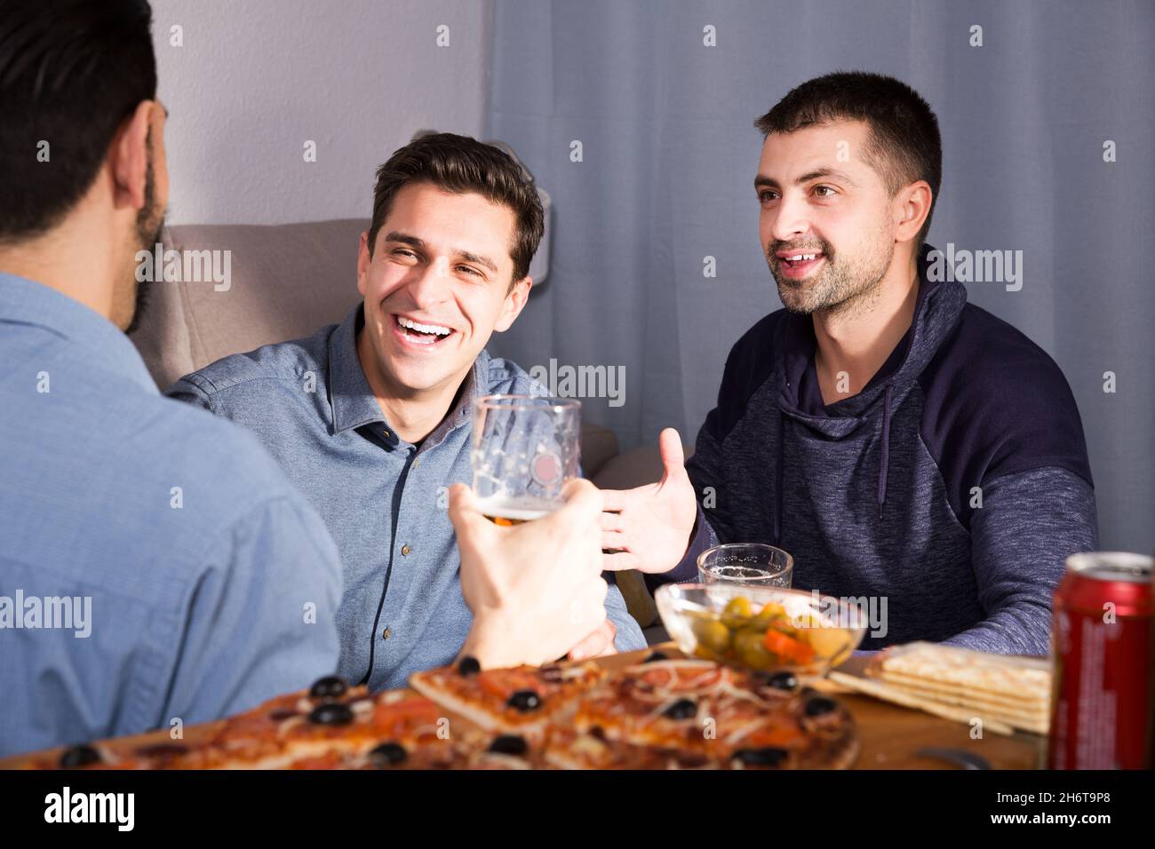 Three men talking and laughing at home Stock Photo - Alamy
