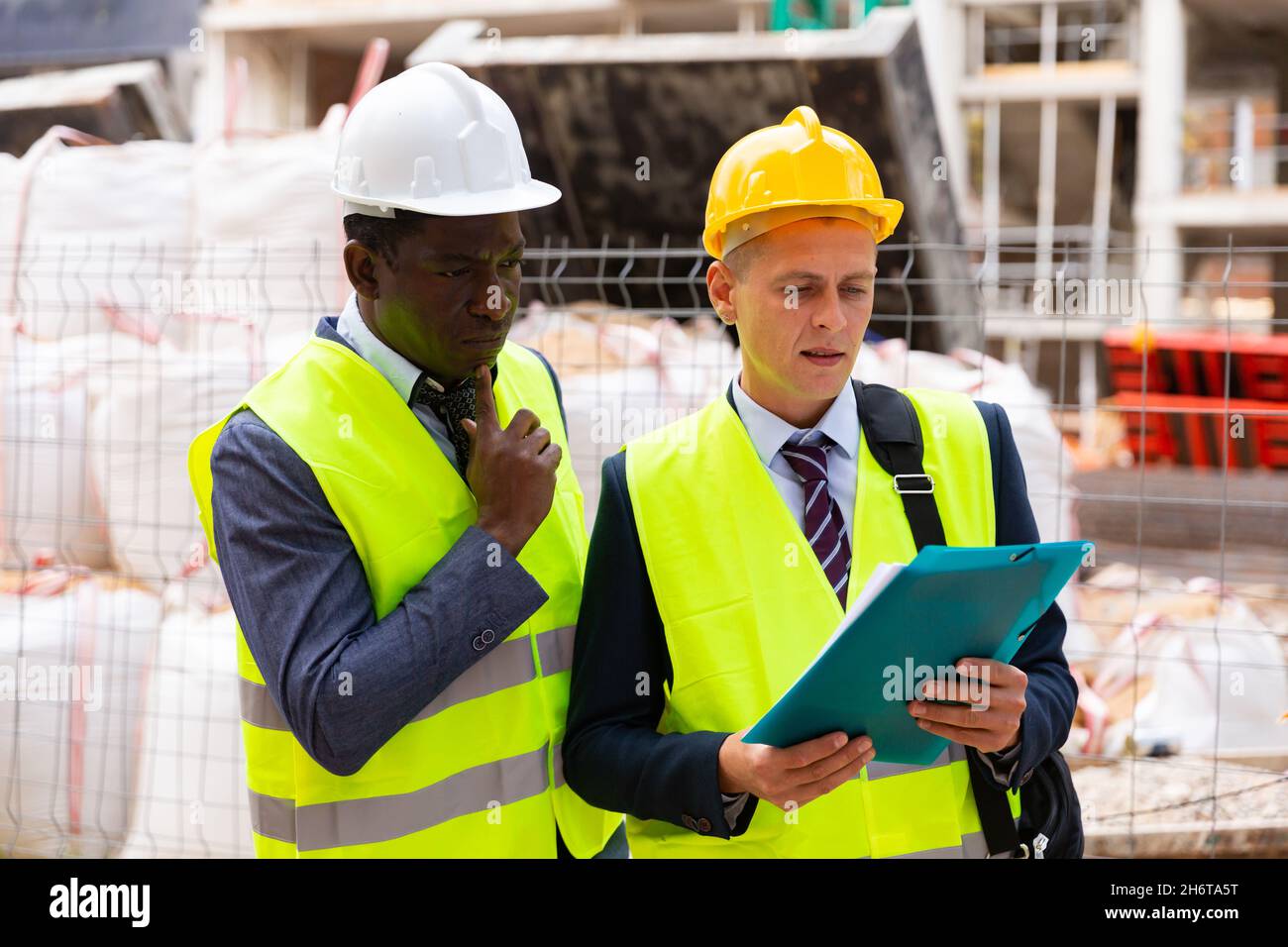 Engineer standing with builder supervising the construction process ...