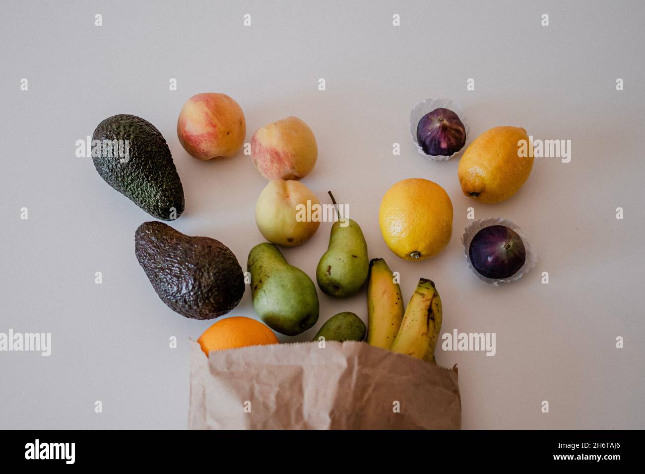 A variety of fruits in a crafted paper bag are lying on the table ...