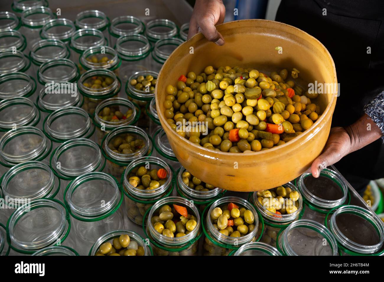 Hands of African worker filling jars with pickled olives Stock Photo ...