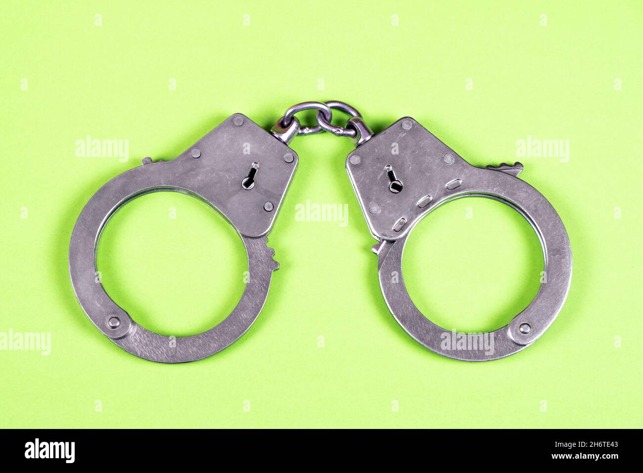 Handcuffs on the Green Paper Background closeup Stock Photo - Alamy