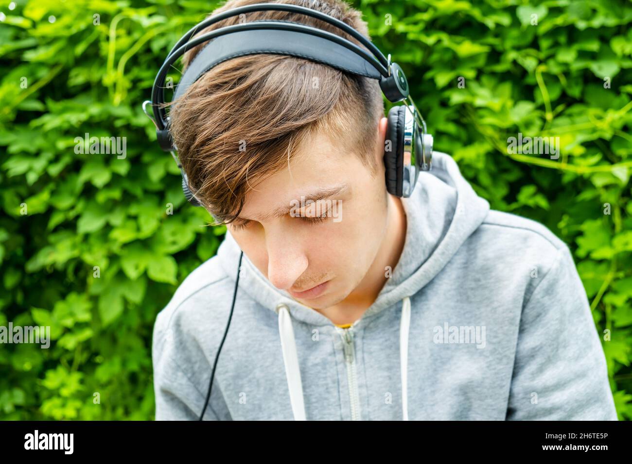 Sad Young Man in Headphones on the Green Leaves Background outdoor ...