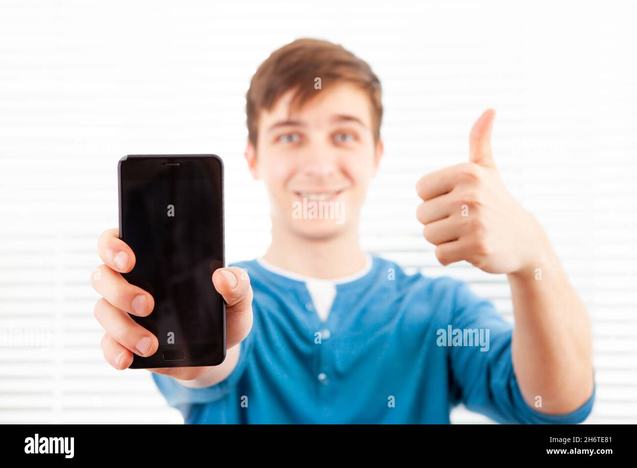 Happy Young Man show a Screen of the Mobile Phone and Thumb Up Gesture ...