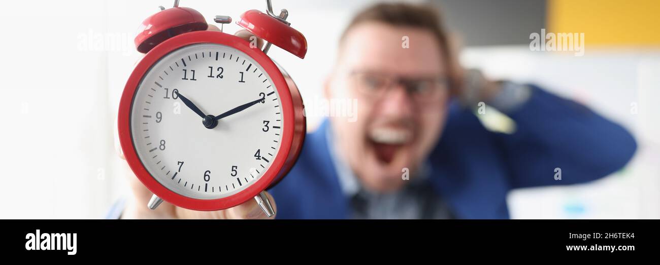 Screaming businessman holds red alarm clock in hands Stock Photo - Alamy