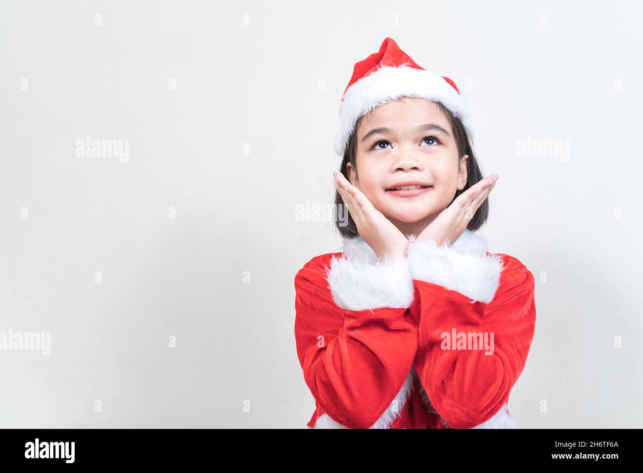 Cheerful Asian female kid wearing Santa Claus clothes on the white ...