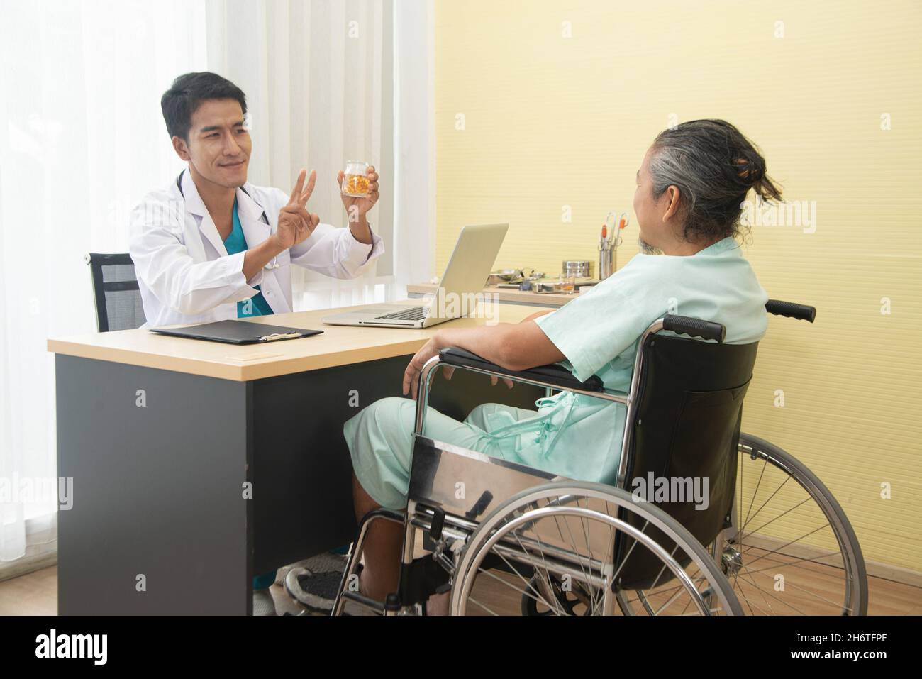An Asian male doctor explains medication to an elderly Asian male ...
