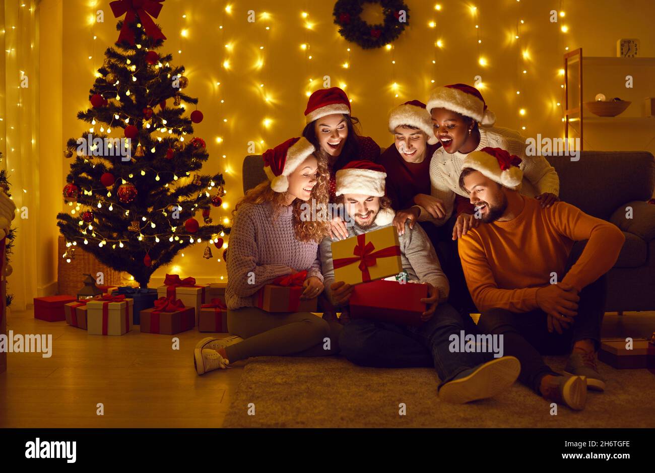 Happy friends open Christmas gift box from which light shines and ...