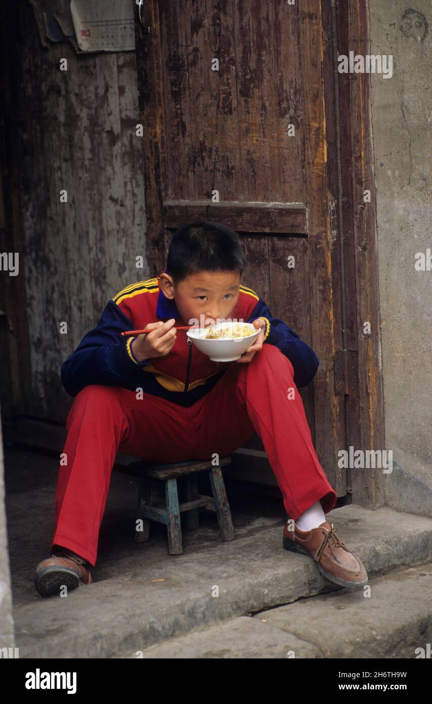 CHINA, BEIJING, YOUNG CHINESE EATING AT THE DOOR OF A HUTONG Stock ...
