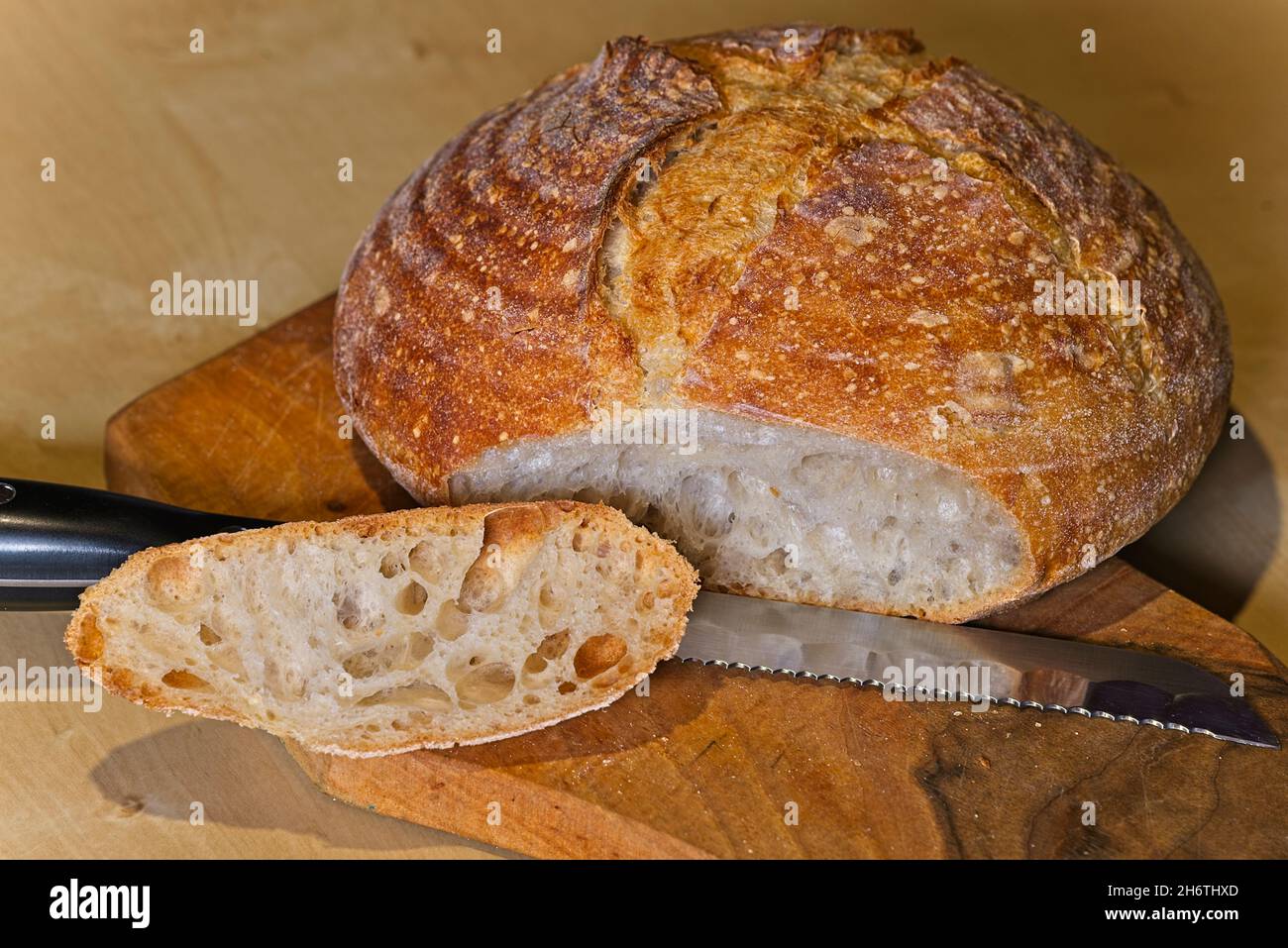 Loaf of home made craft bread on wooden plate with sliced heel and long ...