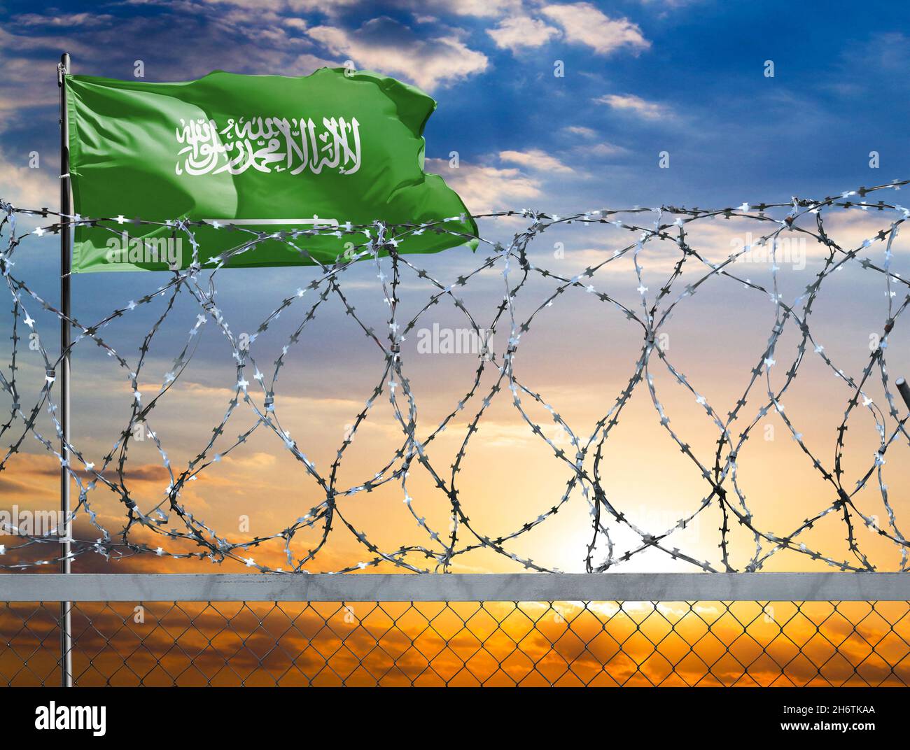 A fence with barbed wire against the background of a colorful sky and a ...