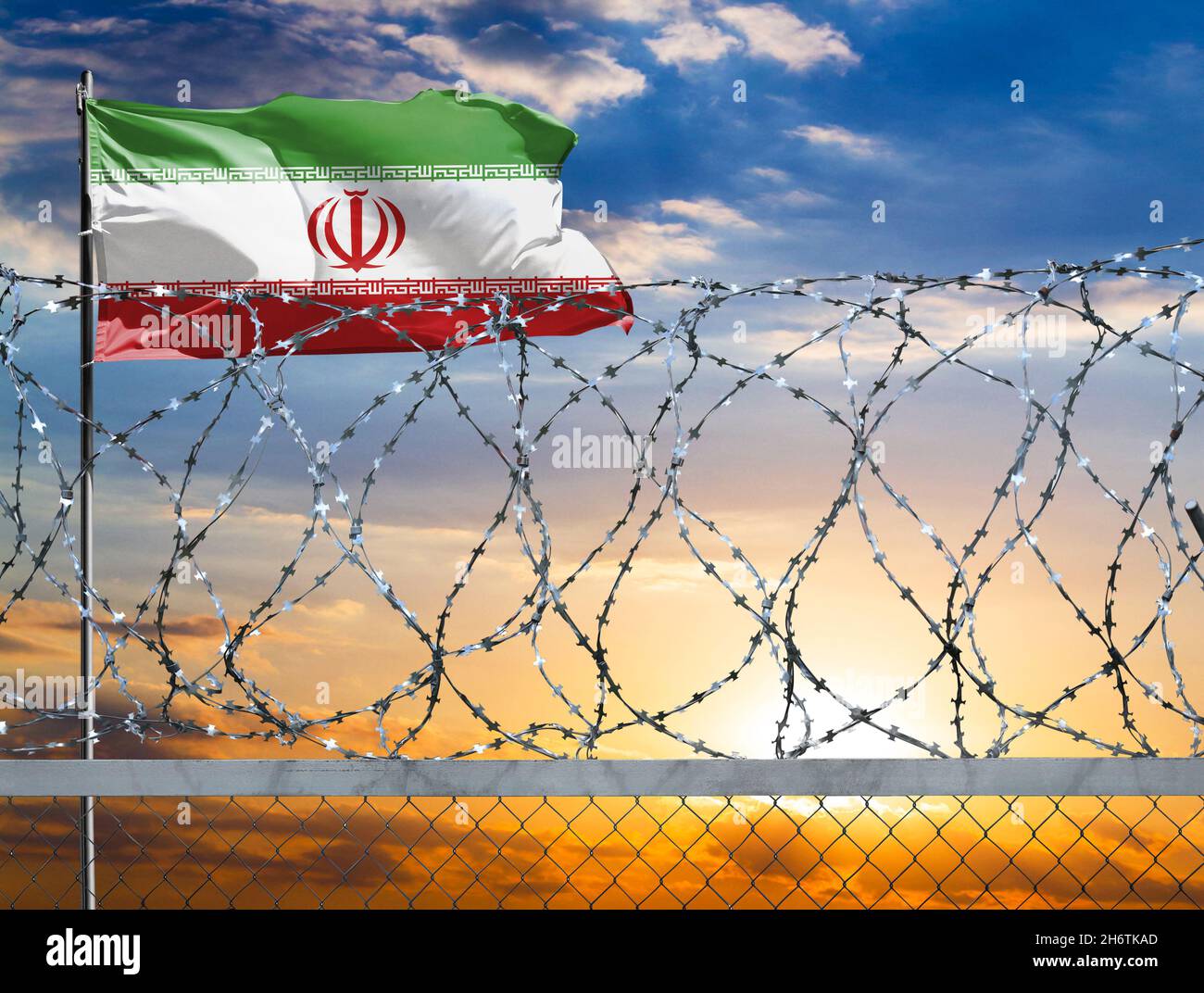 A fence with barbed wire against the background of a colorful sky and a ...
