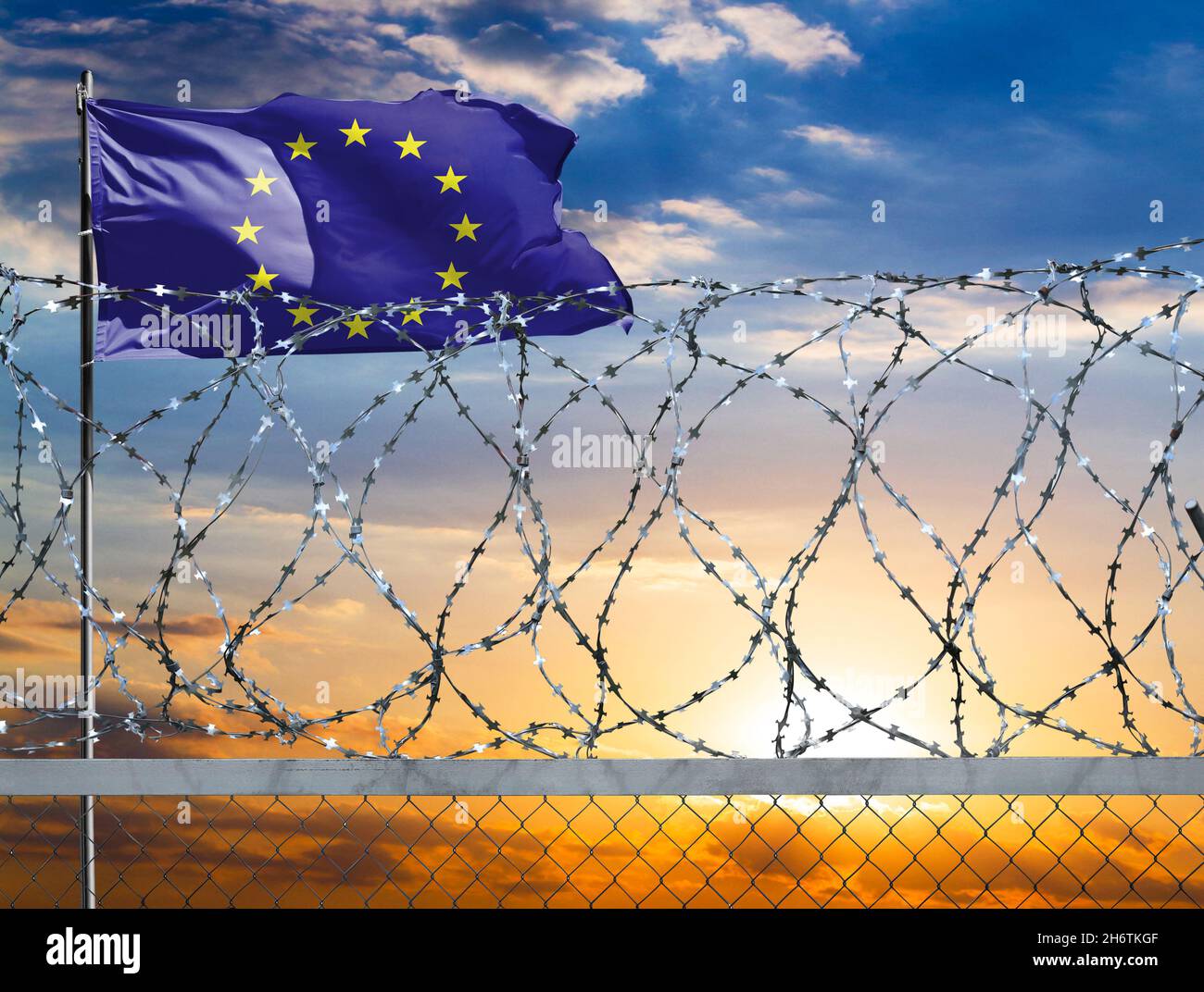 A fence with barbed wire against the background of a colorful sky and a ...