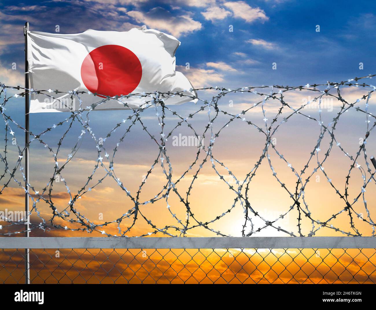 A fence with barbed wire against the background of a colorful sky and a ...
