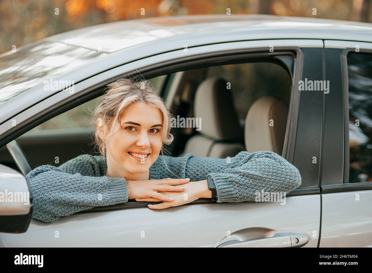 Photo of Young beautiful blonde woman looked out of open car window ...