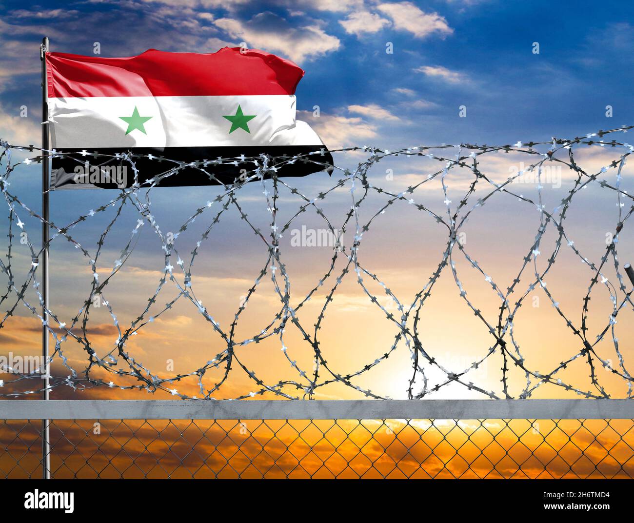 A fence with barbed wire against the background of a colorful sky and a ...
