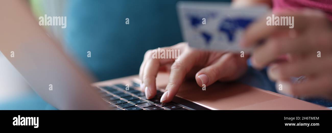 Woman typing on laptop keyboard and holding credit bank card in her ...