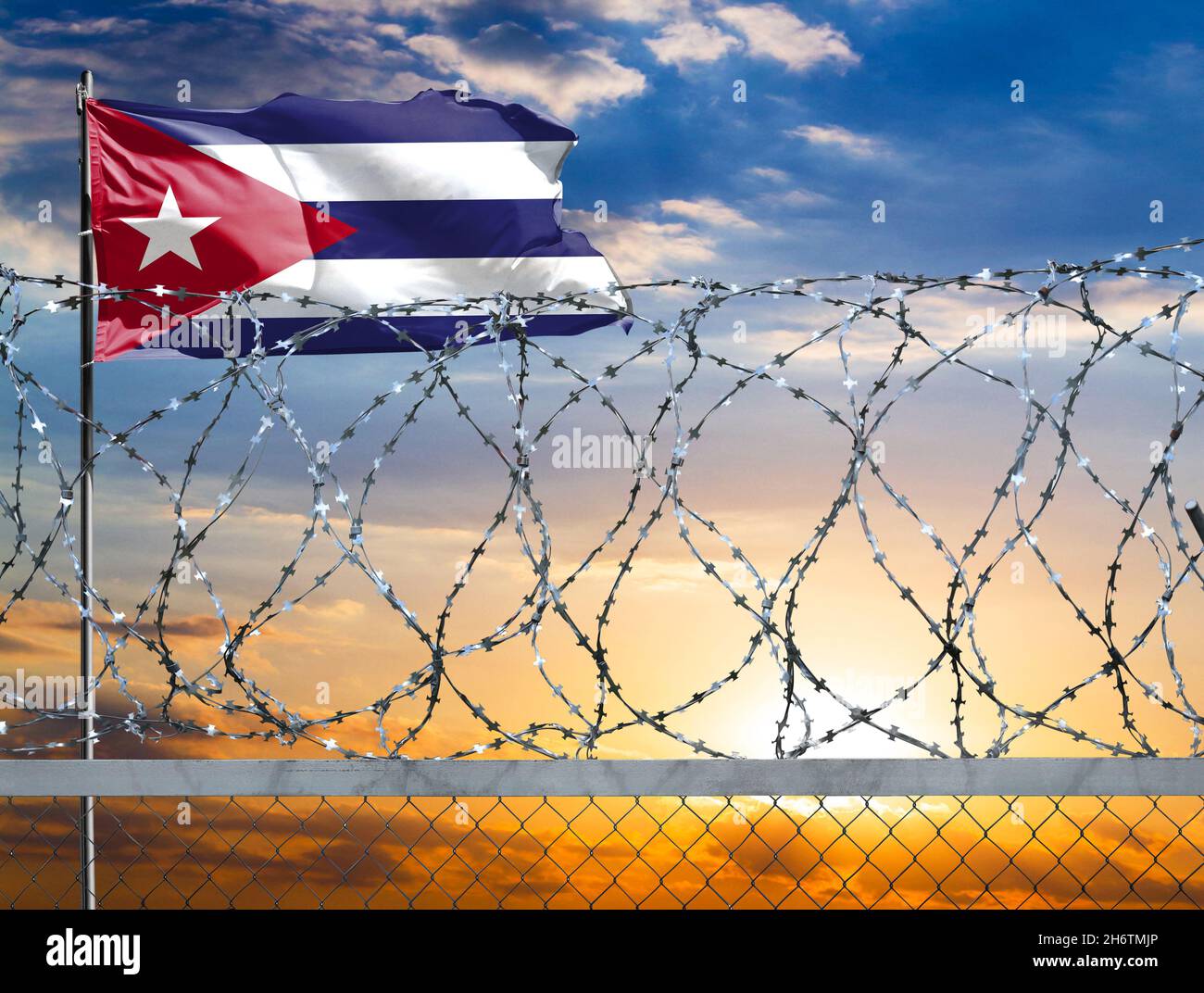 A fence with barbed wire against the background of a colorful sky and a ...