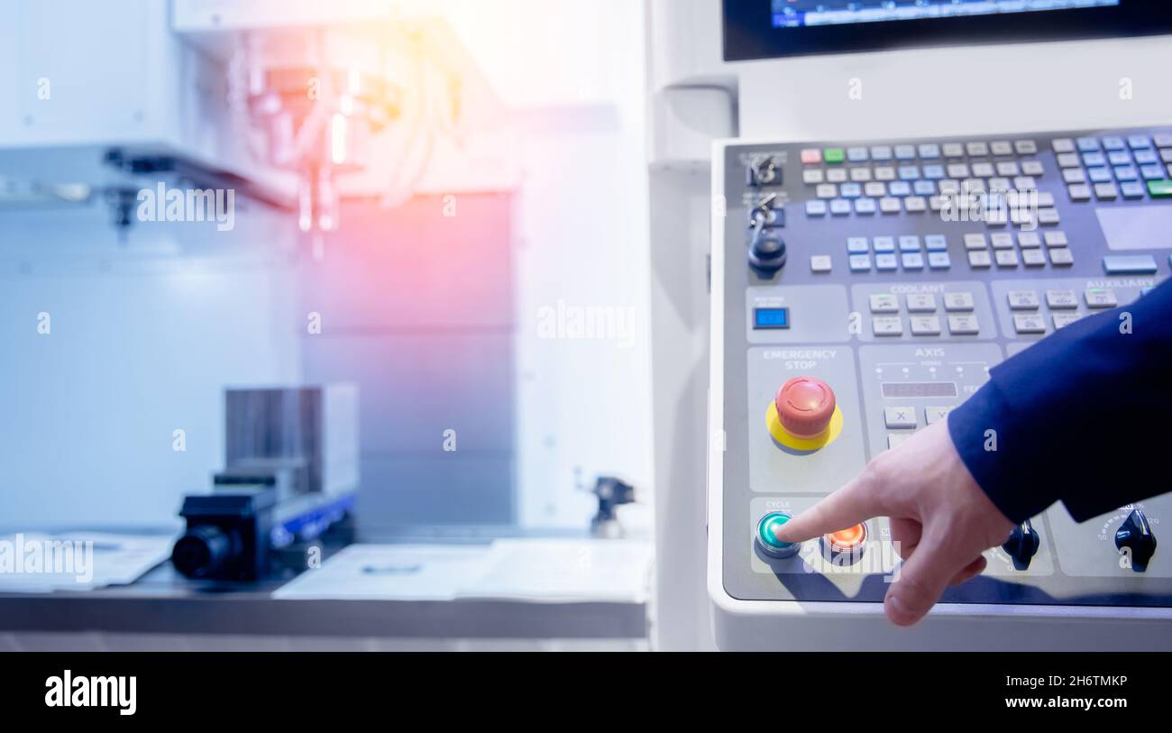 Worker push start control panel of CNC machine at factory floor to get ...