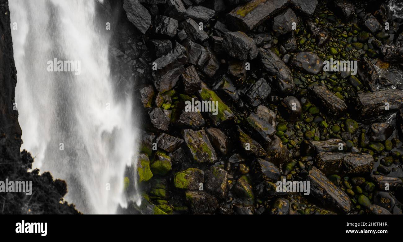 Closeup shot of a waterfall coming over the mossy rocks in Scotland ...
