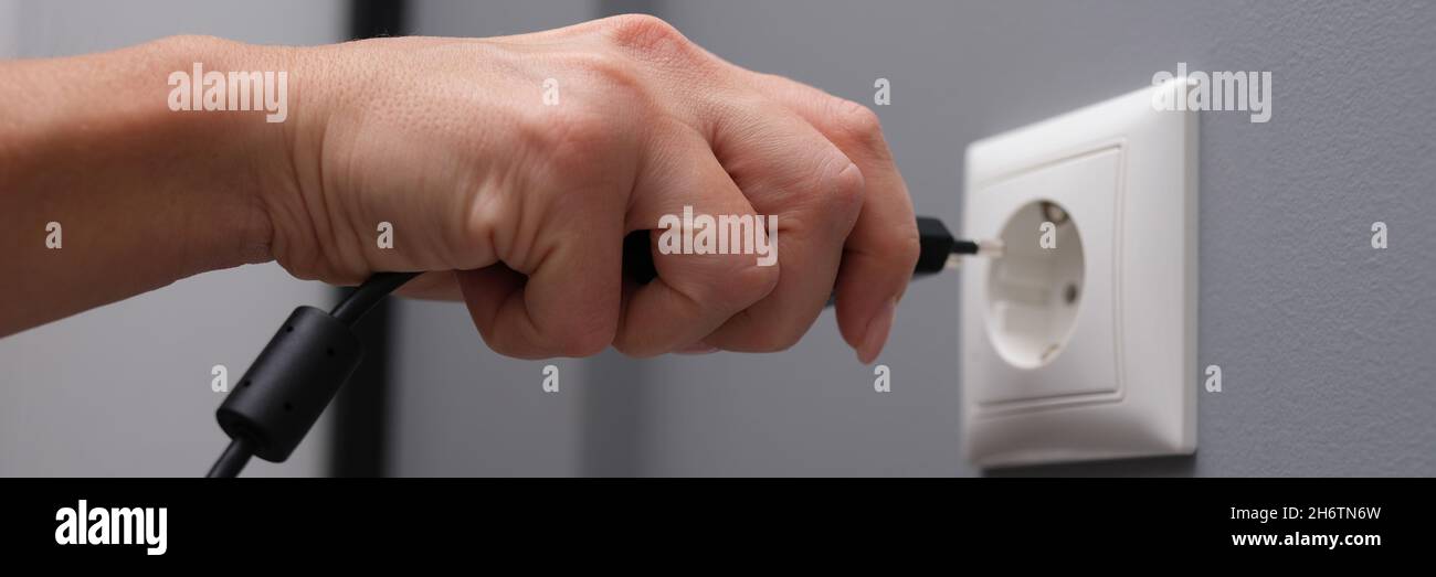 Woman hand inserts electrical plug into outlet closeup Stock Photo - Alamy