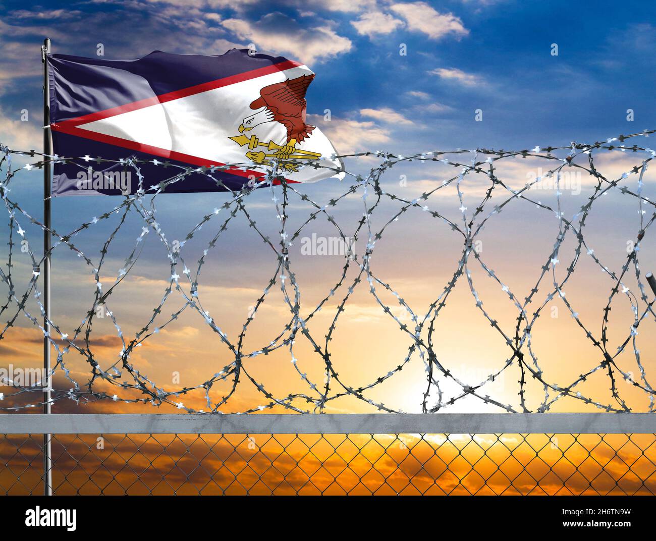 A fence with barbed wire against the background of a colorful sky and a ...