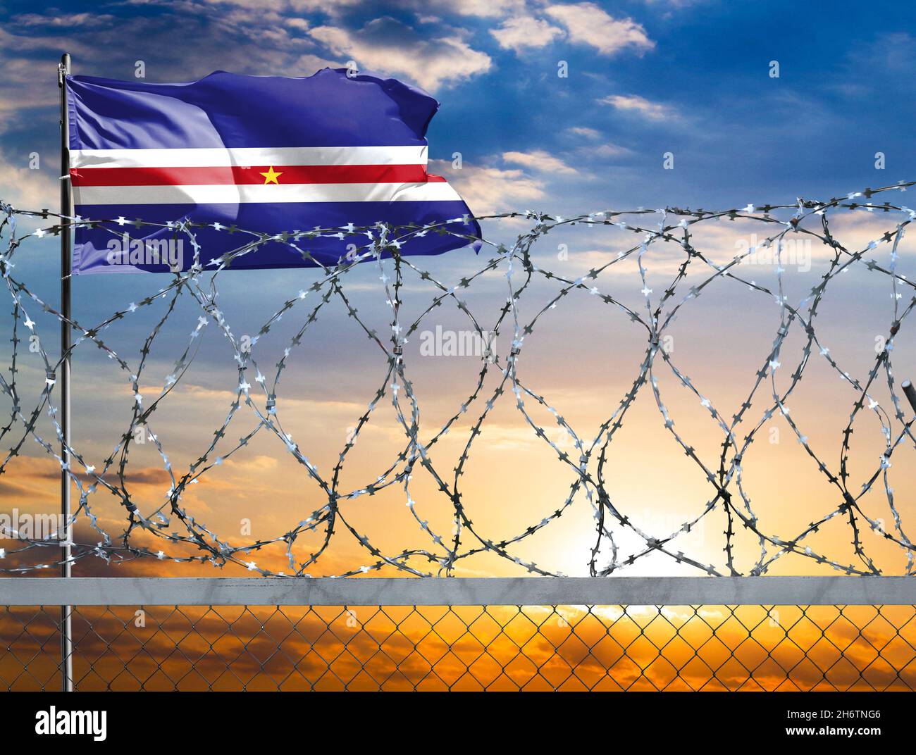 A fence with barbed wire against the background of a colorful sky and a ...