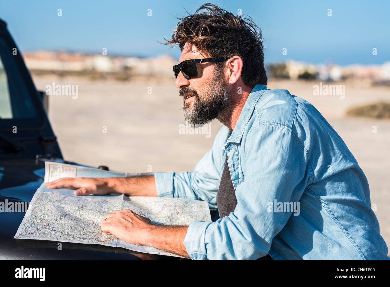 Bearded handsome man choose destination on paper map on the nose of his ...