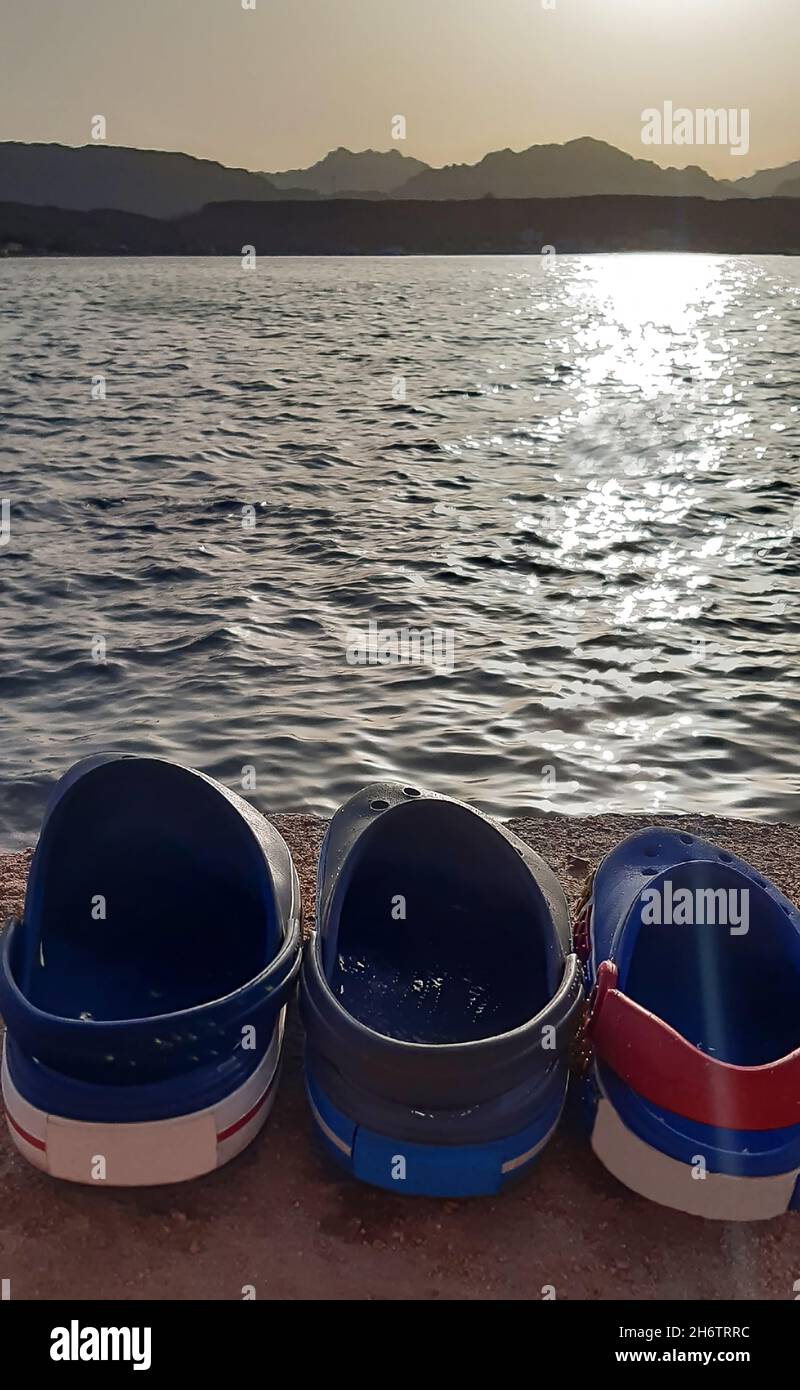 Three multi-colored sandals of different shapes lie in a row on the ...