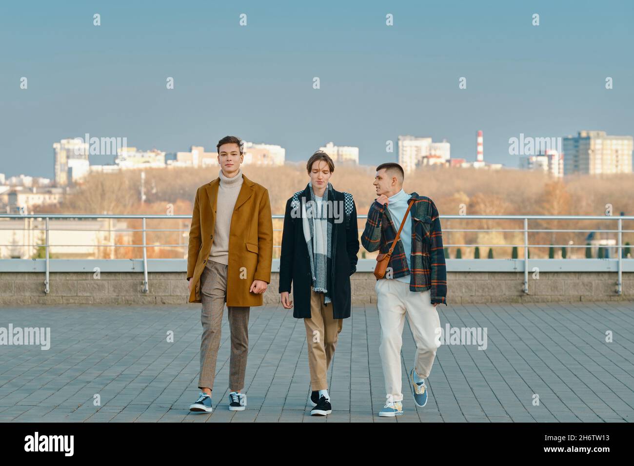 Three young men in casual clothes walking on the street Stock Photo - Alamy