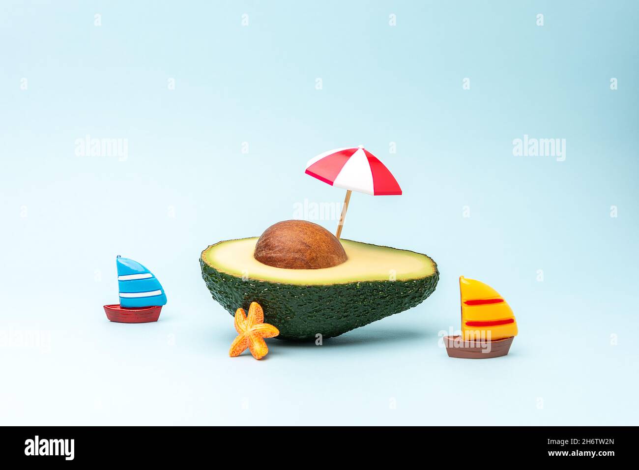 Tropical beach concept made with avocado fruit and sun umbrella ...