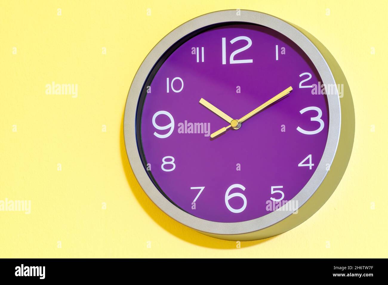 Shot of an indoor purple wall clock on the yellow background Stock ...