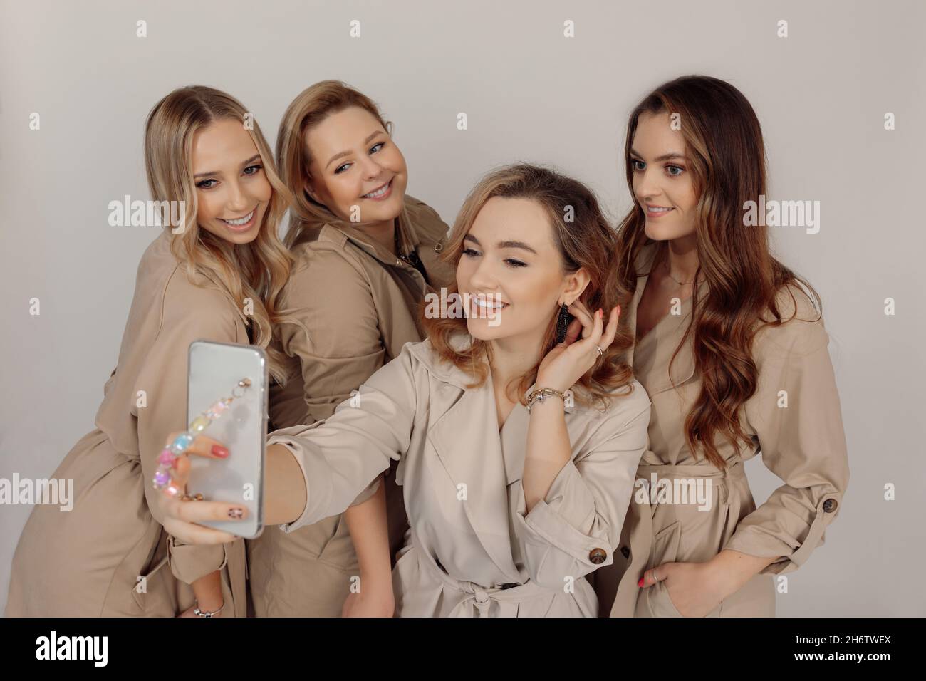 Four cute young positive woman having fun. Beige trench coat. Laughing ...