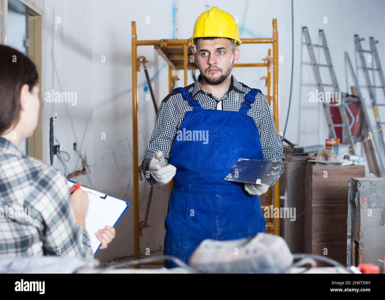 Builder with spatula is clarifying details from client Stock Photo - Alamy