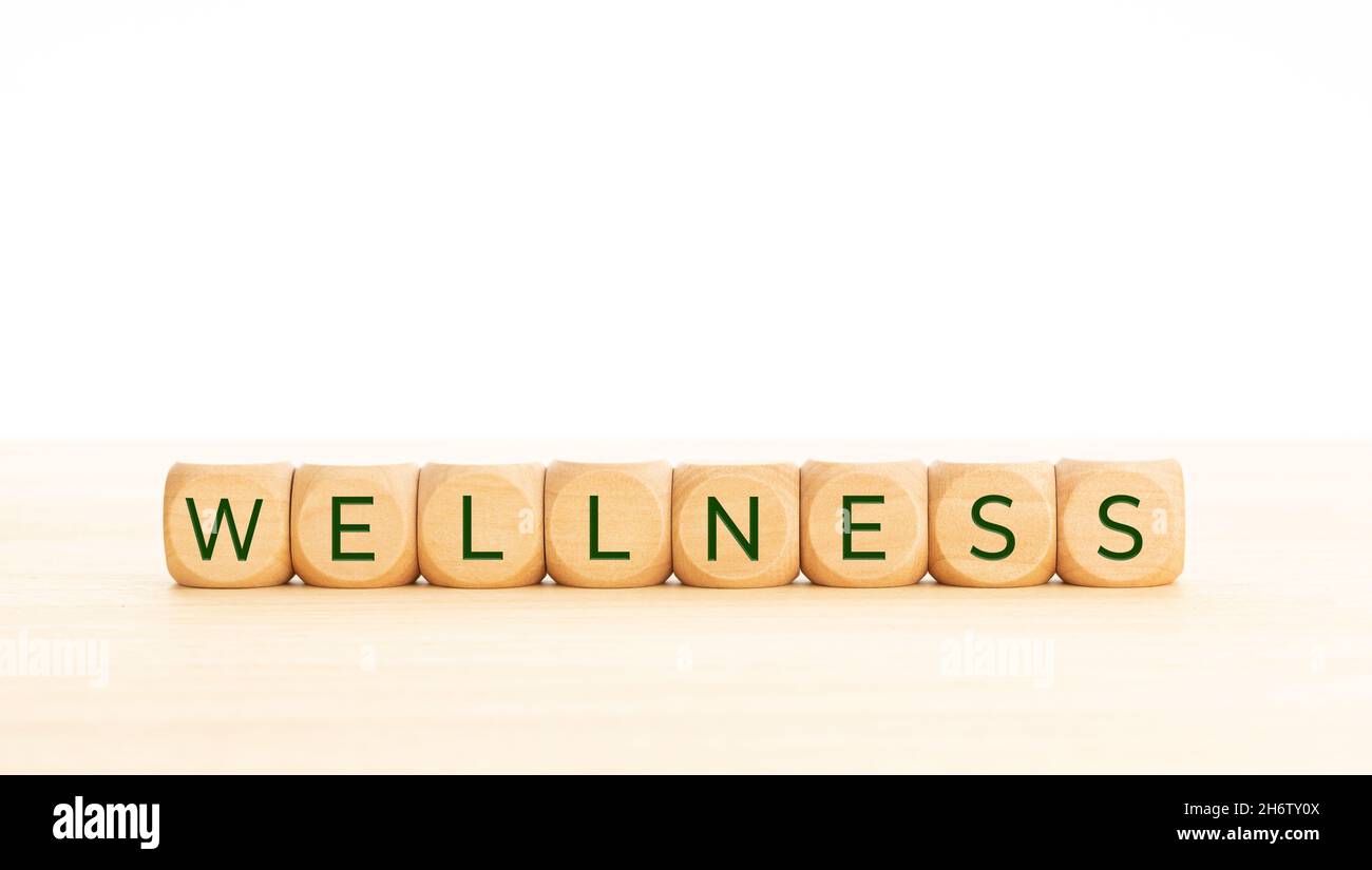 Wellness word in wooden blocks on table. White background. Copy space ...
