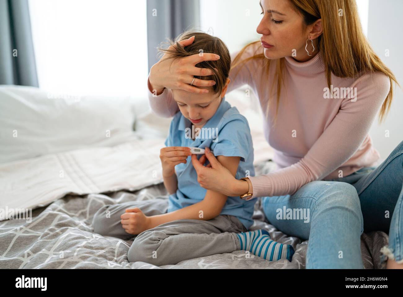 Mother measuring temperature of her ill kid. Sick child with high fever, mother holding ...