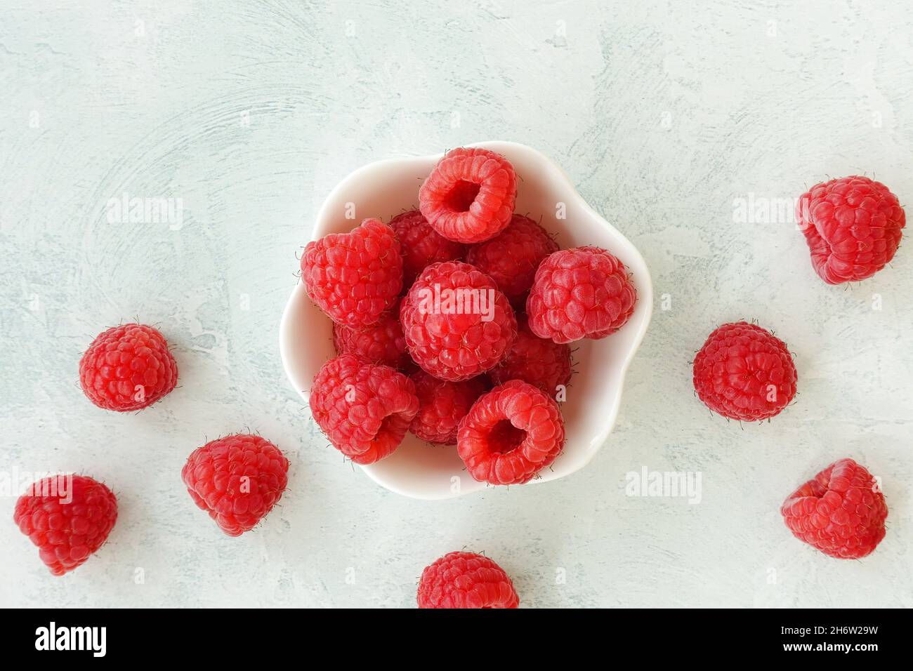 Closeup top view of raspberries in a cute white bowl and raspberries ...