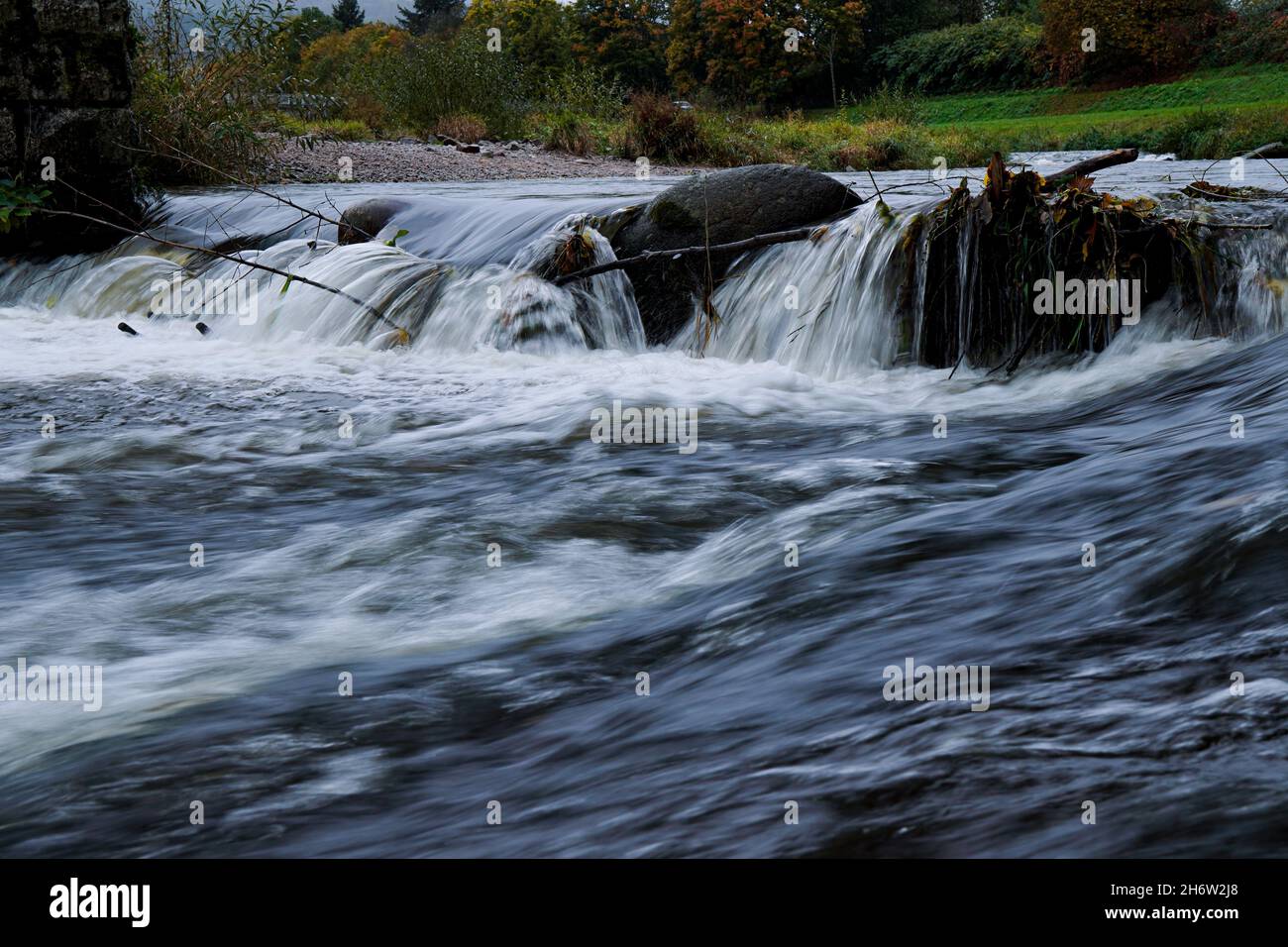 Waterfall and powerful river rapids with trees in the background during ...