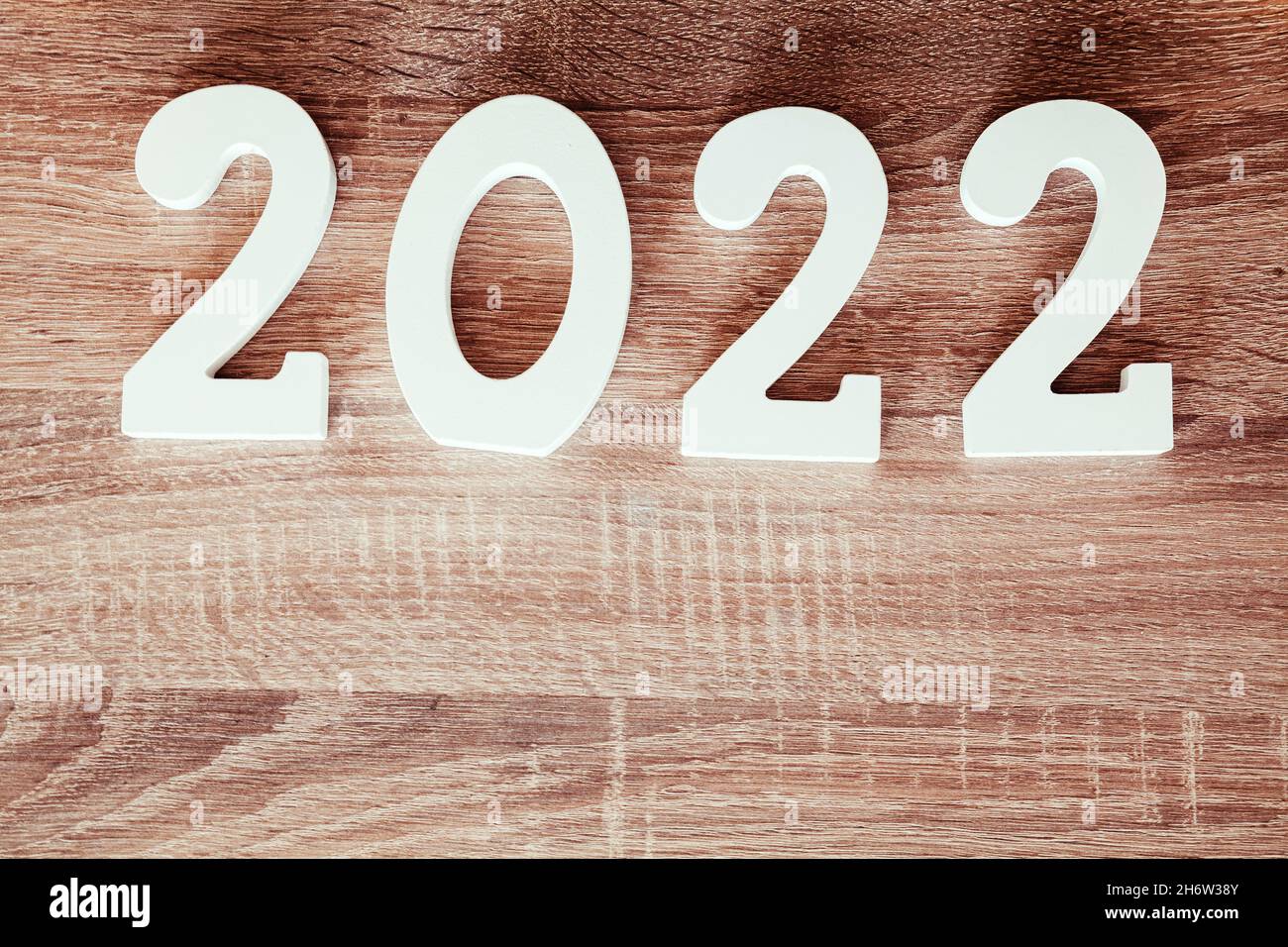 The number 2022 made of white wood on an oak wood board. Under the ...