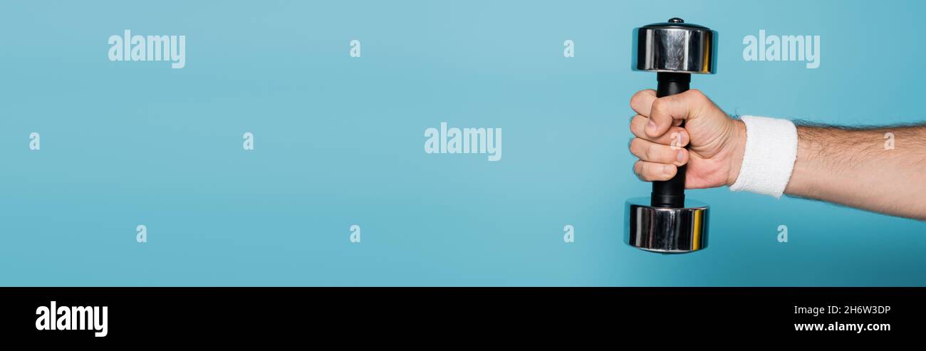 cropped view of sportsman holding heavy dumbbell on blue, banner Stock ...