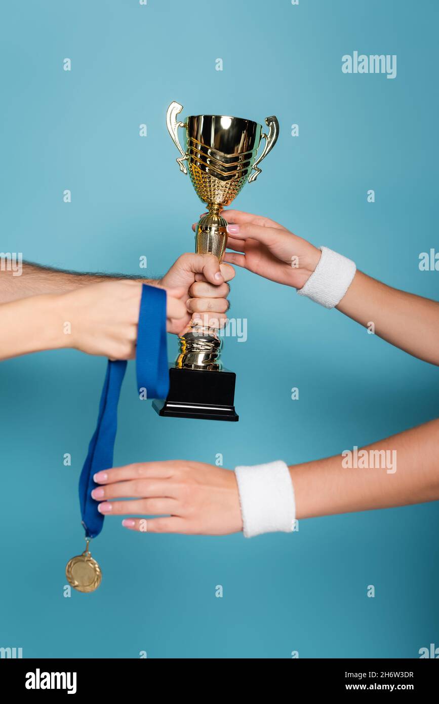 cropped view of man giving golden trophy and medal to female champion ...