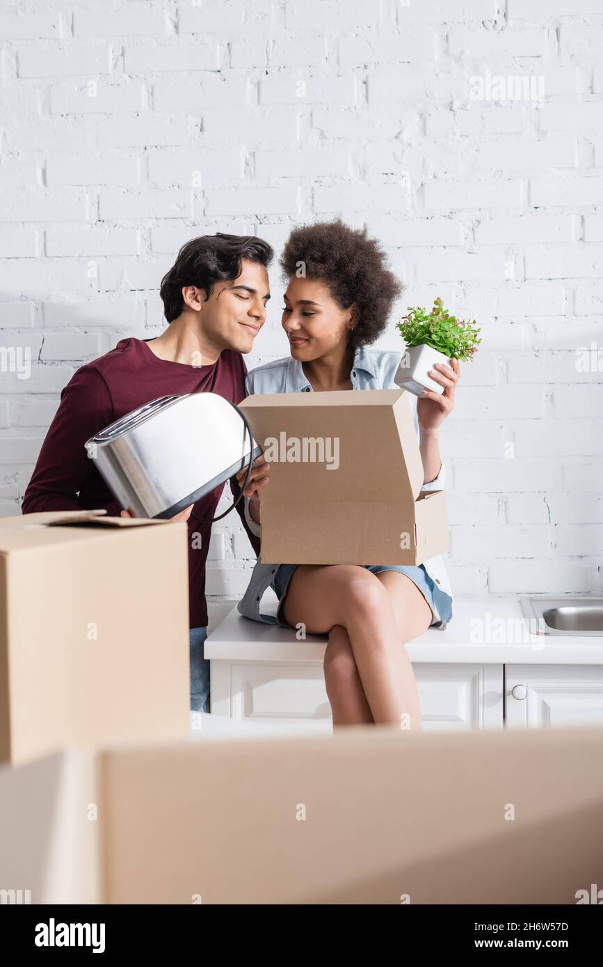 happy young man holding toaster near joyful african american girlfriend ...