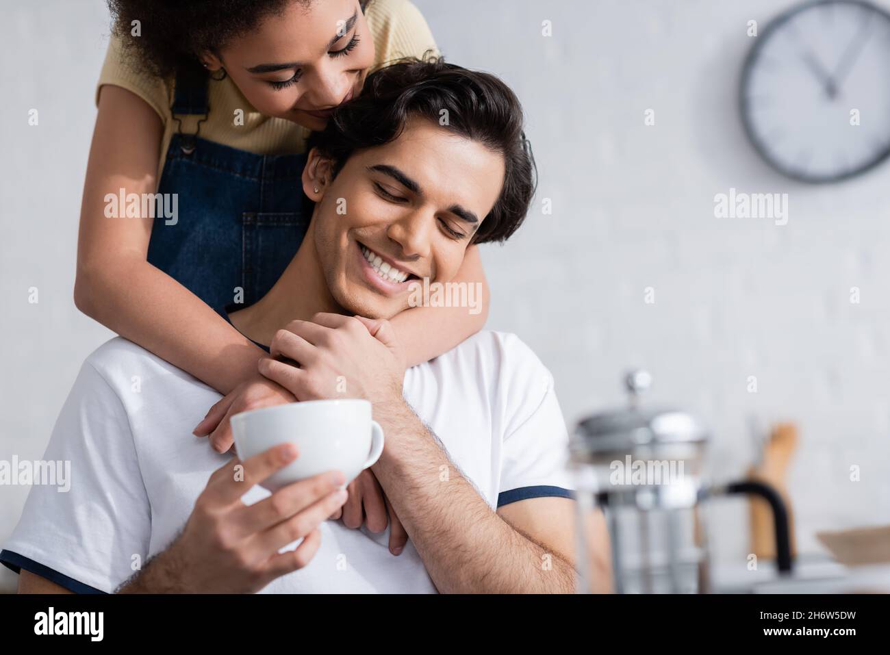 happy african american woman hugging boyfriend with cup of tea in ...