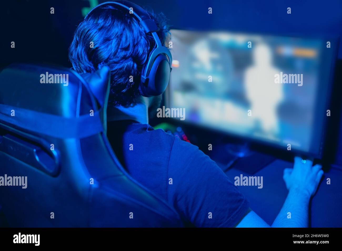 Neon color, young man esports playing online shooter with machine guns ...