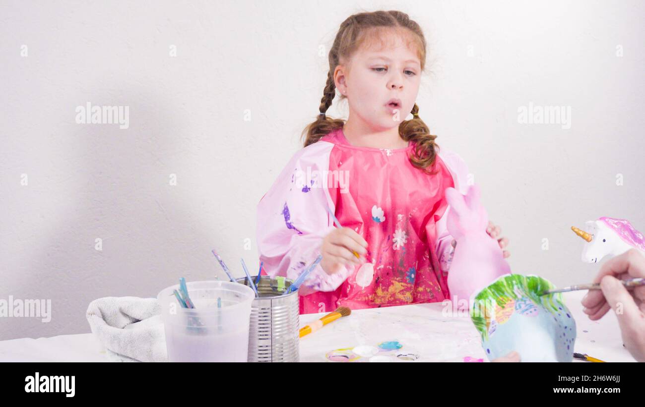 Little girl painting paper mache figurines with acrylic paint for her ...