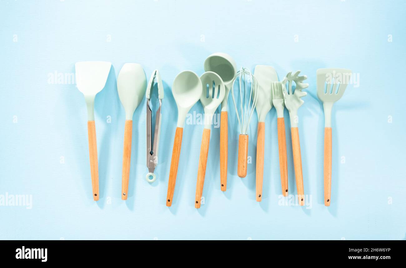 Flat lay. New blue silicone kitchen utensils with wooden handles on a ...